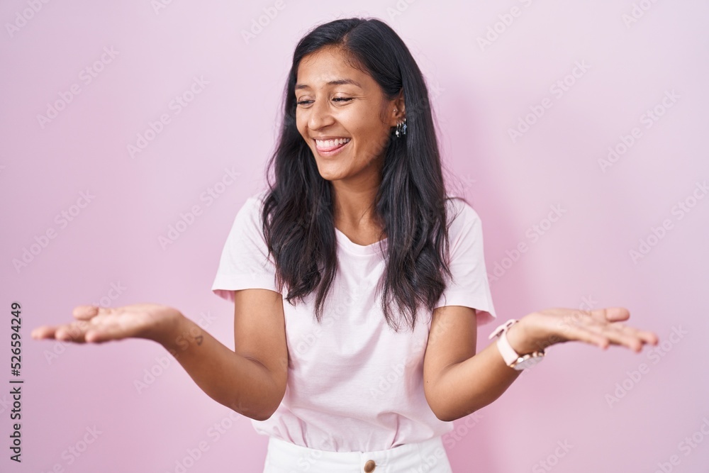 Young hispanic woman standing over pink background smiling showing both ...