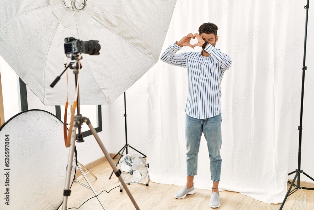 Arab young man posing as model at photography studio doing heart shape ...