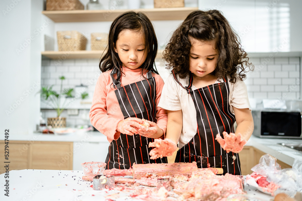 Foto Two diverse kid girls having fun cooking cake bakery together in ...