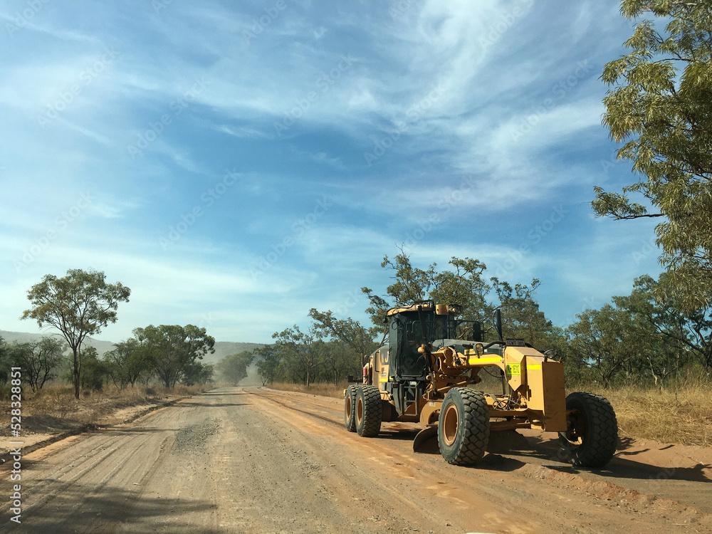 Earth moving grader working on a heavily corrugated road section of the ...