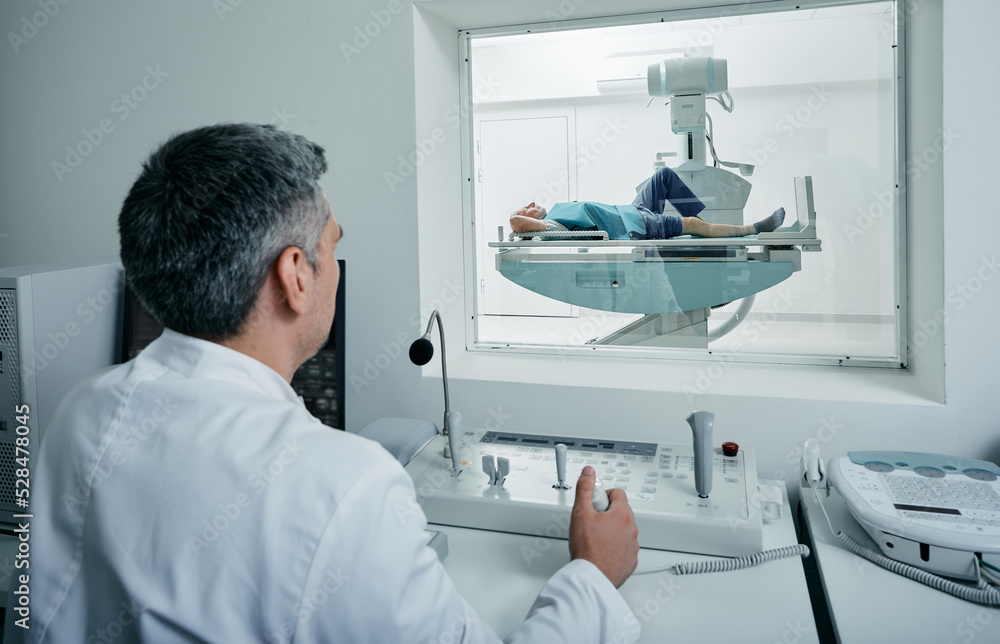 Radiologist controls X-ray process sitting behind protective window in ...