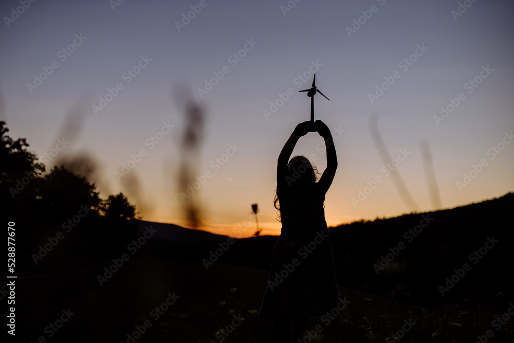 Little girl standing in nature with model of wind turbine. Concept of ...