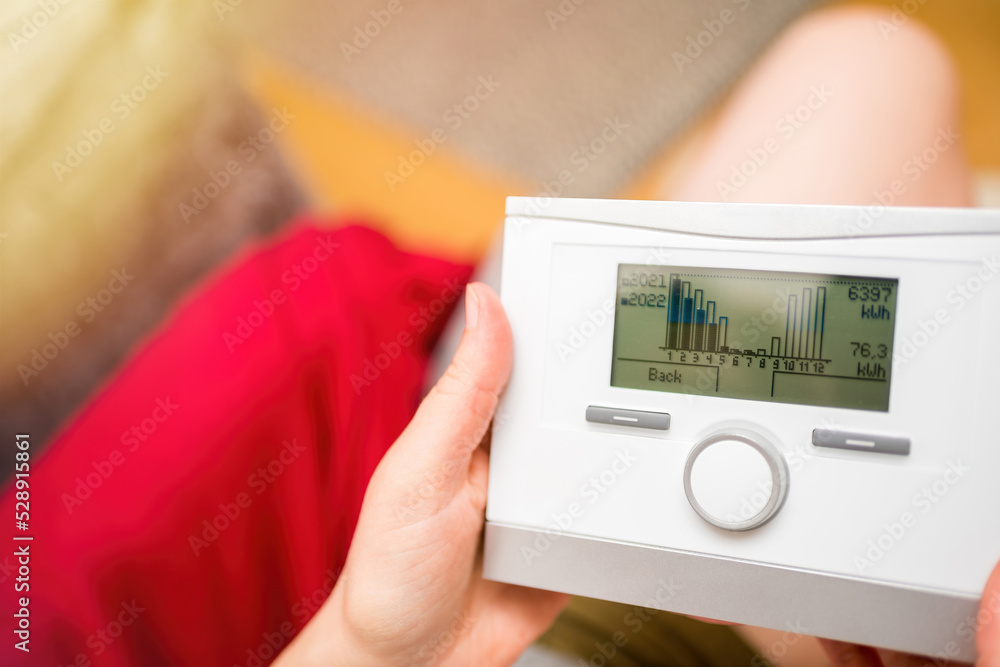 Hand holding new weather compensating programmable room thermostat ...
