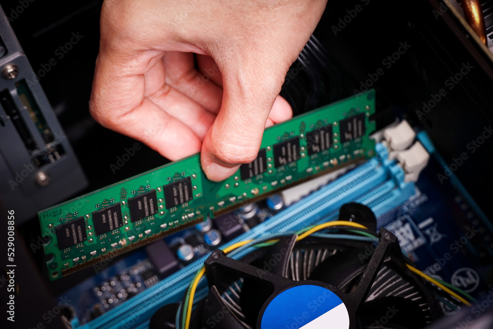Computer technician installs new RAM DDR memory (Random-access memory) into a PC. Computer ...