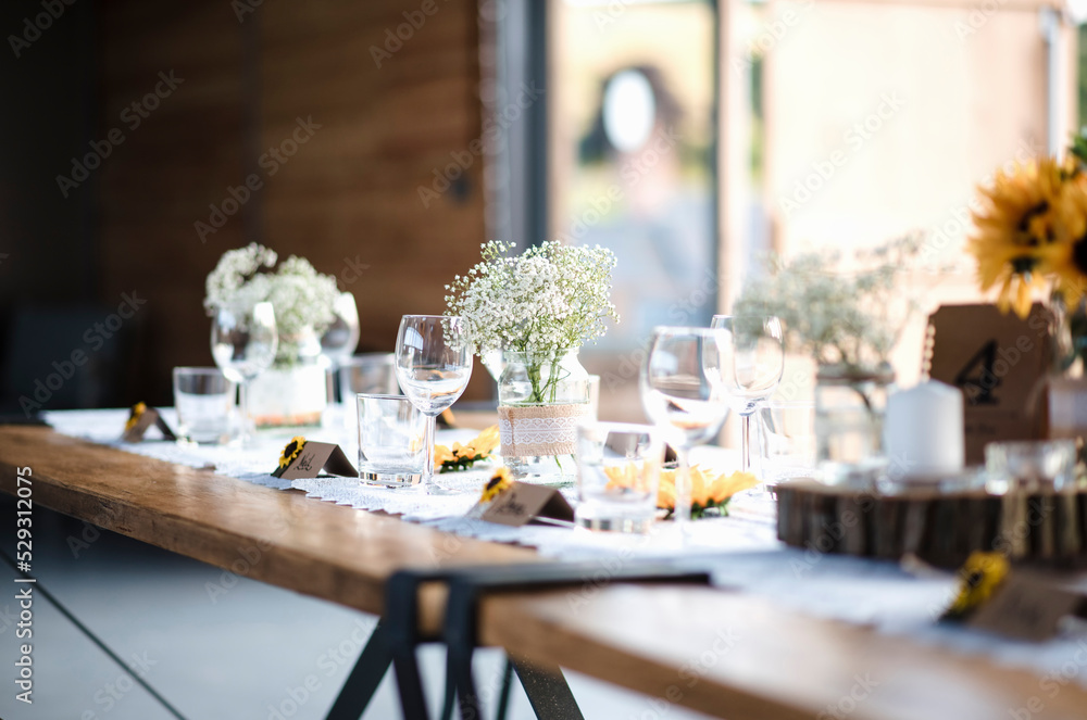 Flowers with drinking glasses and name tags arranged on dining table in ...