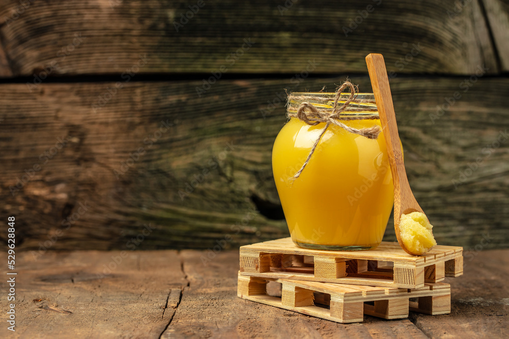 ghee oil. Ghee or clarified butter in jar on a wooden background ...