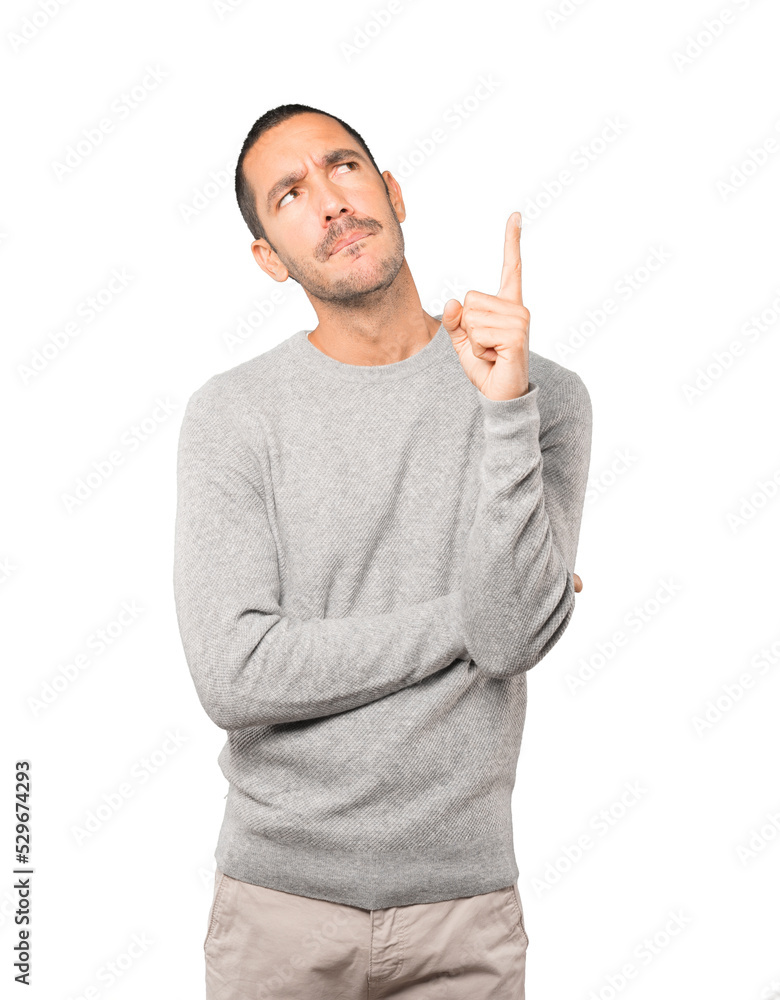 Hesitant young man pointing up with his finger Stock Photo | Adobe Stock