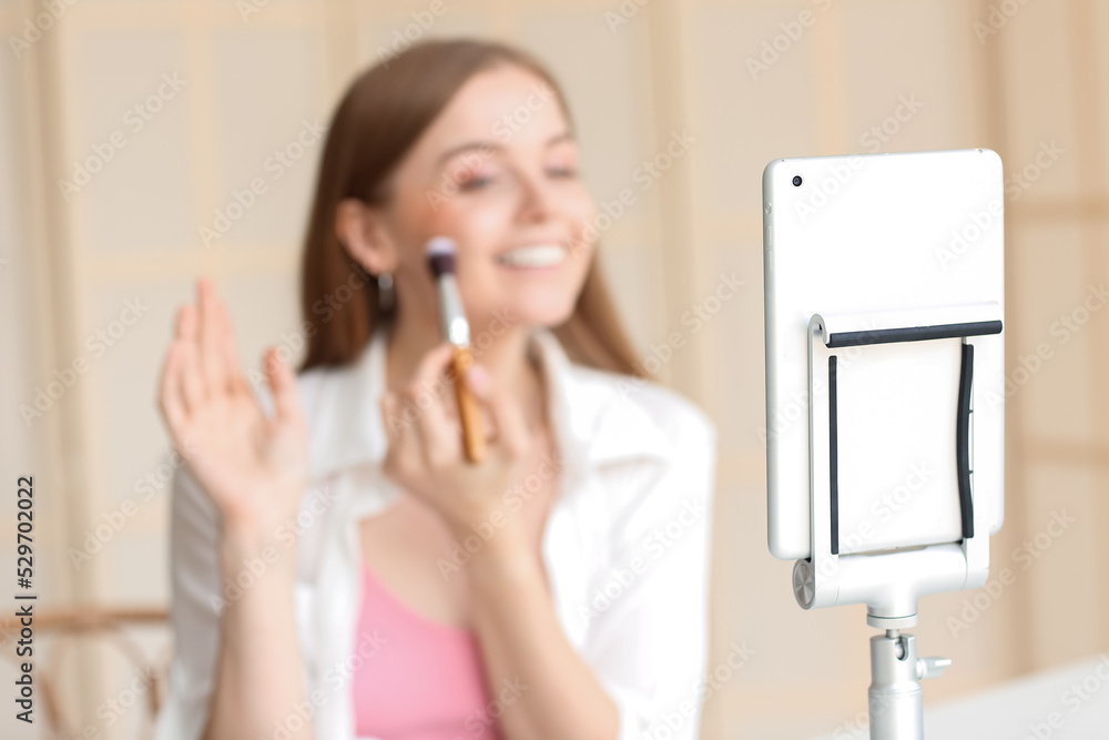 Tablet computer of female beauty blogger applying powder while ...