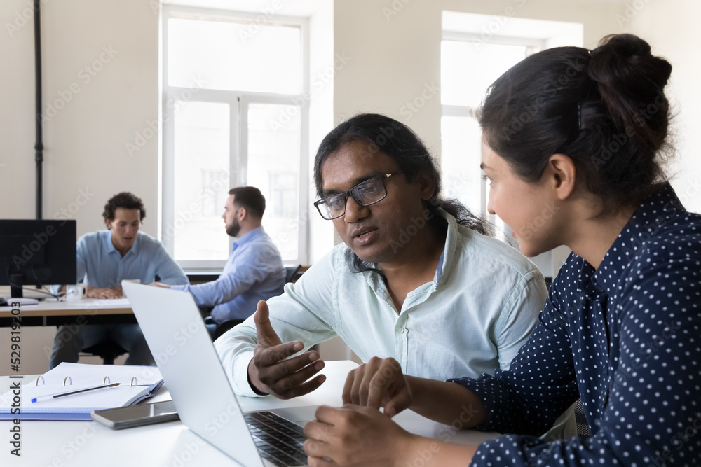 Two Indian employees collaborating on project, sitting at work table ...