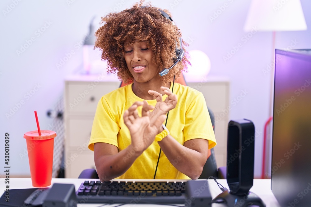 Young hispanic woman with curly hair playing video games wearing ...