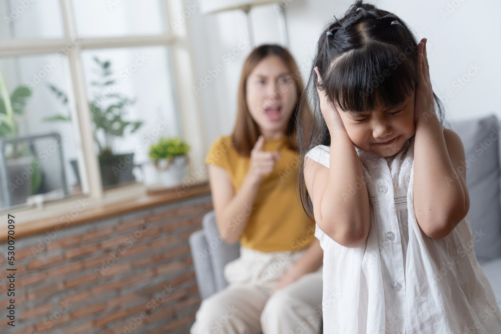 Portrait of Asian little girl close her ear while angry mother yelling about her stubborn for ...