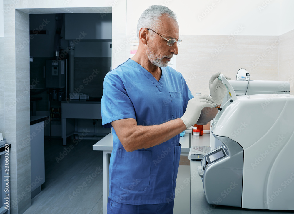 Laboratory assistant loading blood sample into ESR analyzer ...