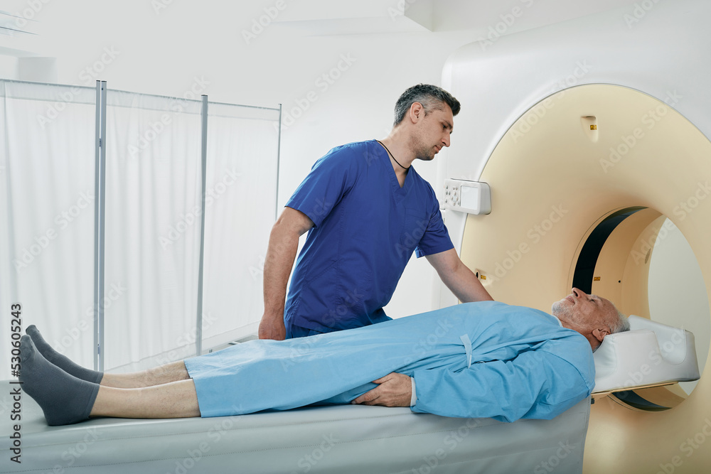 Computed Tomography. Male medical worker helping senior patient during ...