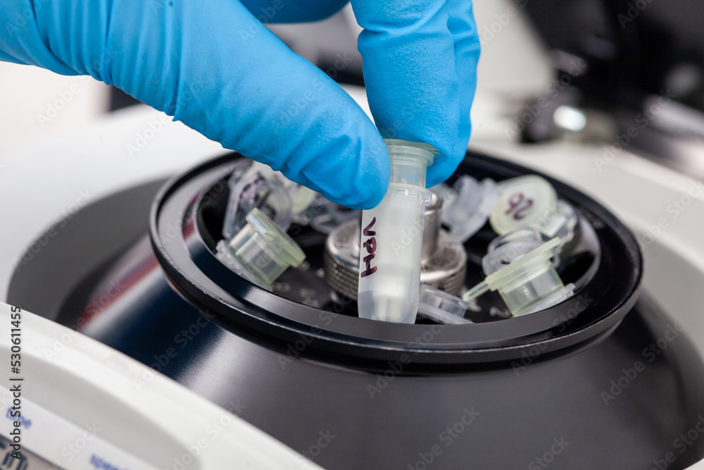 Closeup of a scientist hand placing a tube into an small table ...