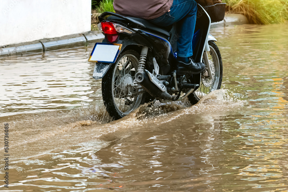 Man ride motorcycle passing through flooded road. Riding motorbike on ...