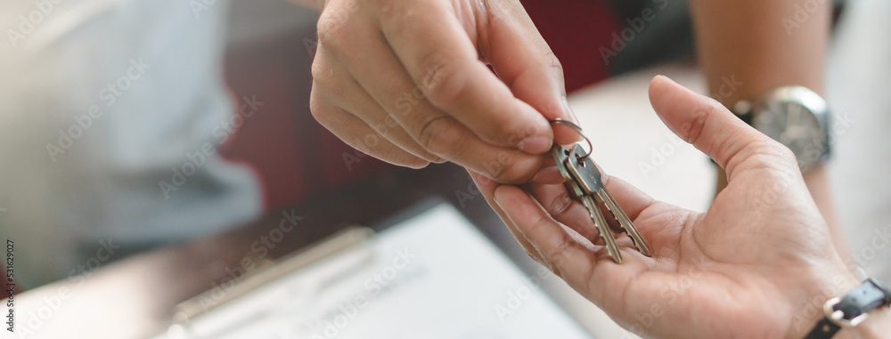 Concept young couple moving house. Hand of realtor agent giving keys of ...