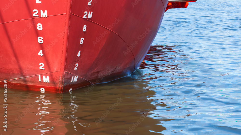 Draft mark numbers on red steel hull surface of nautical vessel while ...