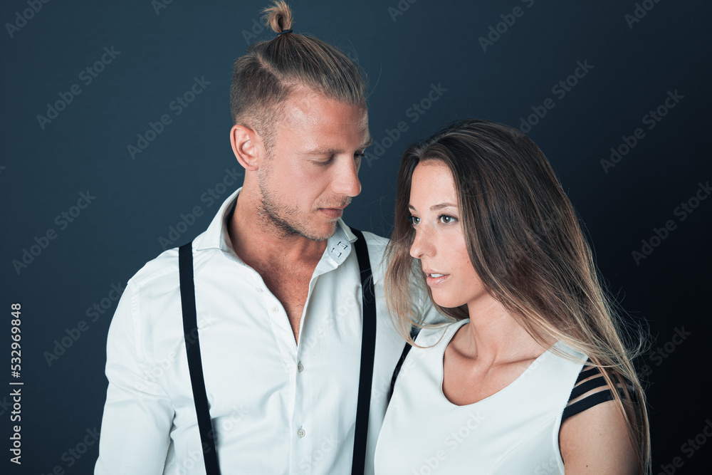 serious couple stand next to each other while man look to woman and she ...
