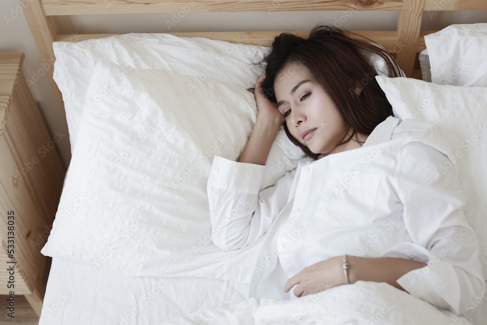 Young depressed asian woman lying and hugging pillow while crying on ...