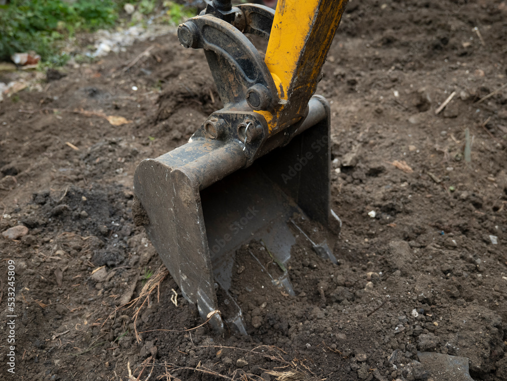 close up of mini digger bucket excavating the ground in a garden work ...