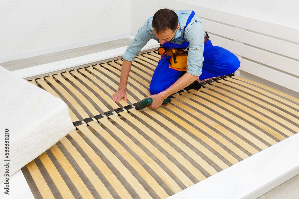 The furniture assembler assembles the bed, twists the screws on the ...