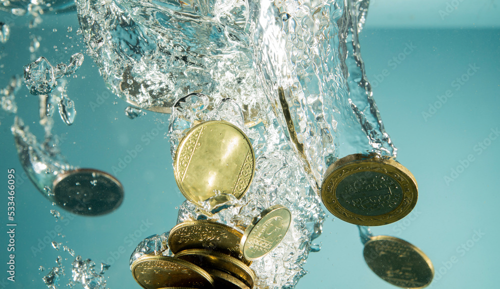 Gold coins dropped into water. Splash of coins falling into the water ...