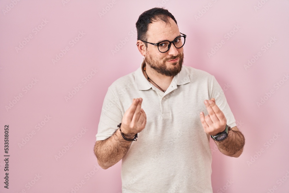 Plus size hispanic man with beard standing over pink background doing ...