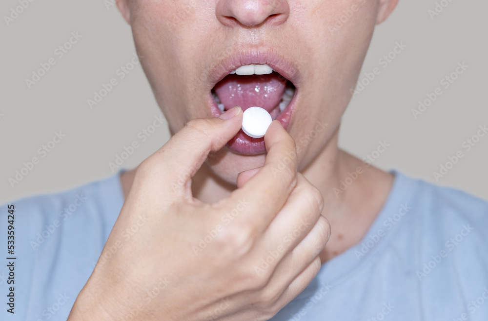 sore throat and runny nose treatment. woman using lozenge candy spray ...