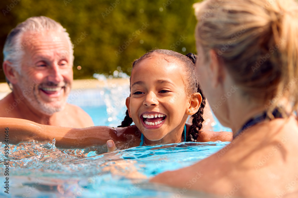 Grandparents Teaching Granddaughter To Swim On Family Summer Holiday In ...