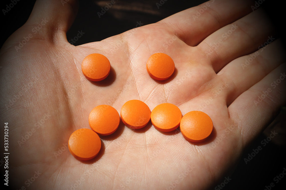 Concept - the negative impact of drugs. Sad face of orange pills on a ...