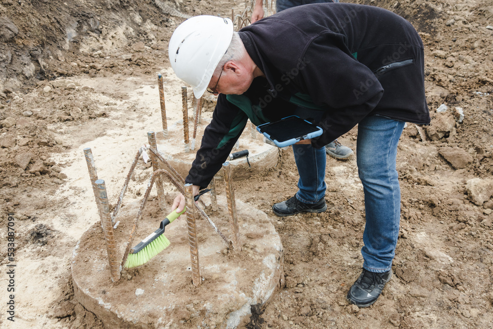 Piles cleaning. Engineer clears a place for pile integrity test. Pile ...