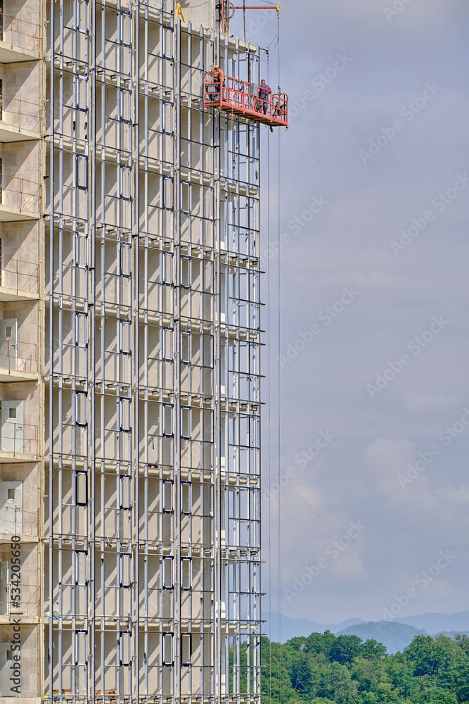 Suspended construction cradle with builders at high altitude. Mobile ...