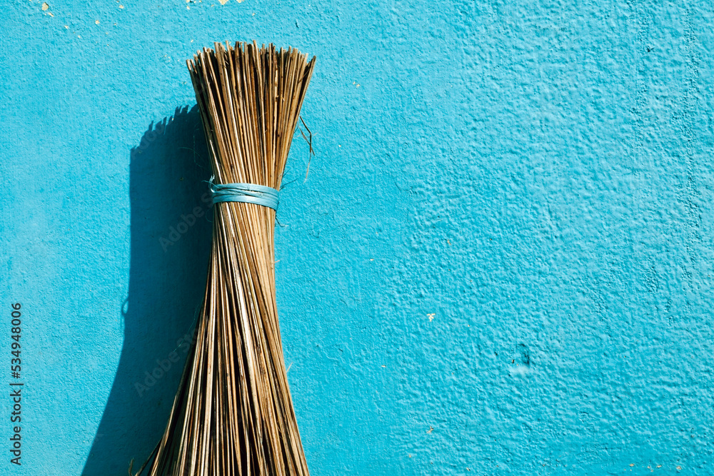 Coconut broom stick isolated in blue color painted wall background ...