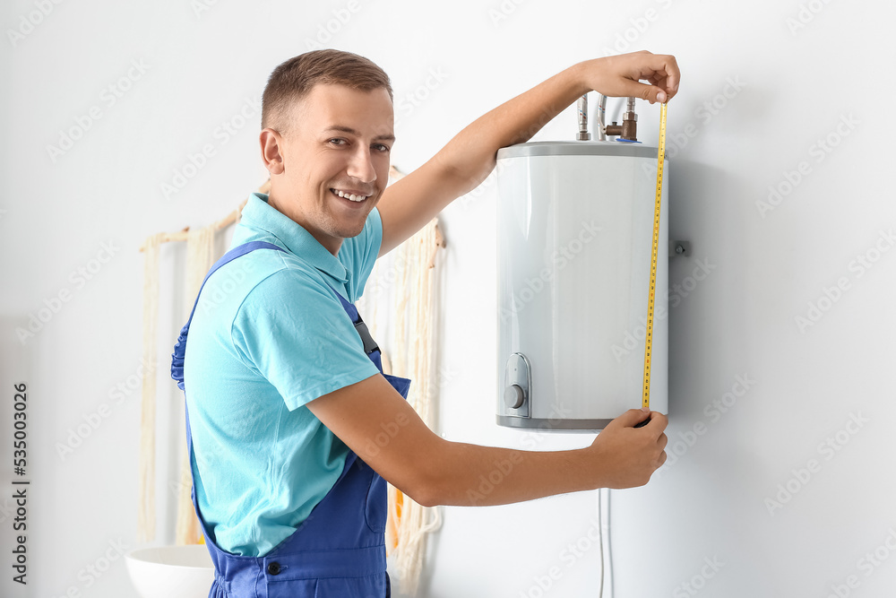 Male plumber installing boiler in bathroom Stock Photo | Adobe Stock