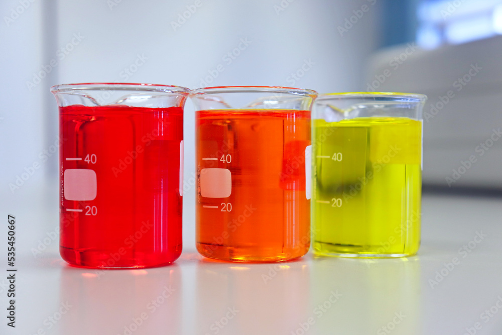 The beakers glassware on bench laboratory with red orange, yellow ...