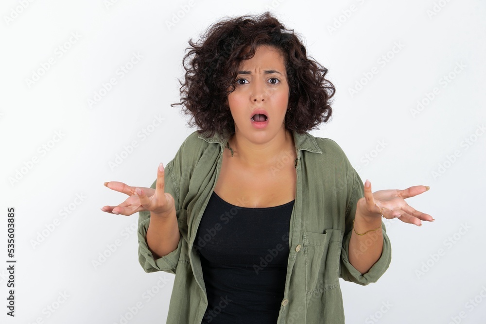 Frustrated young beautiful woman with curly short hair wearing green ...