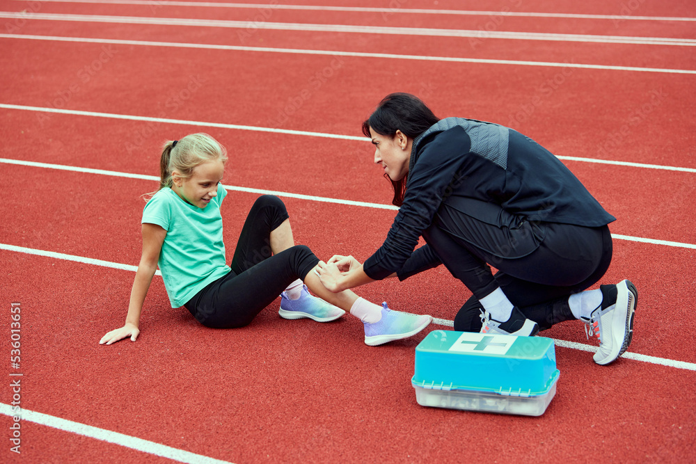First aid for a young athlete at stadium. Sport teen girl suffering ...