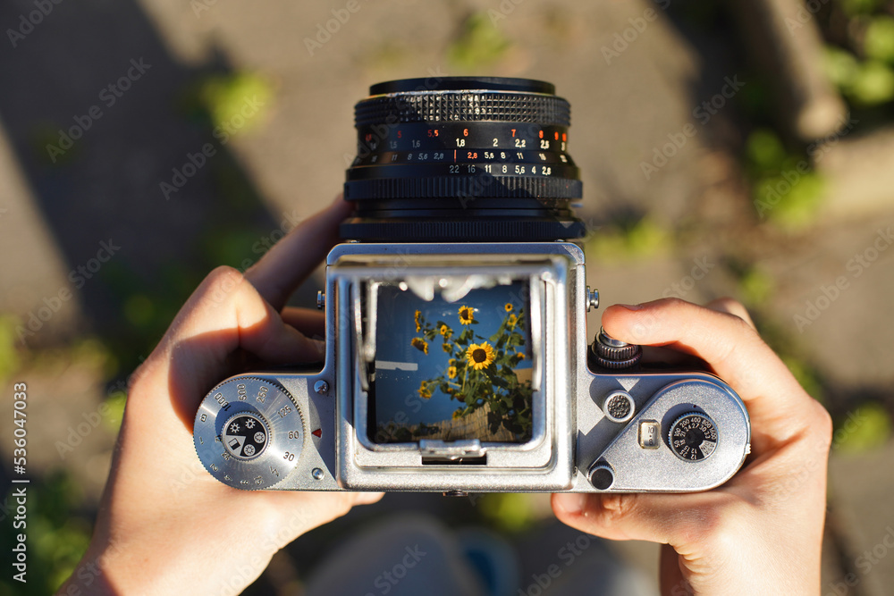A photographer holding a vintage analog photo camera focusing ajusting ...