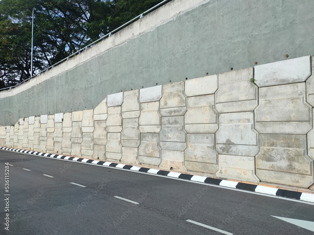 Precast concrete retaining wall panels are installed in layers as a ...