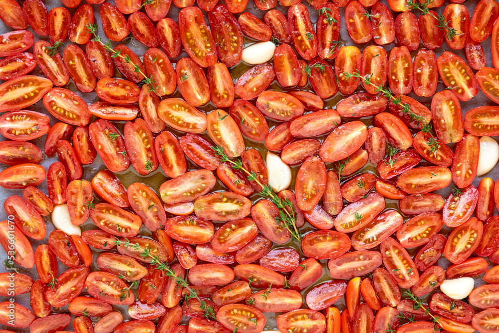 Tray of cherry tomato with cloves of garlic and thyme springs prepared ...