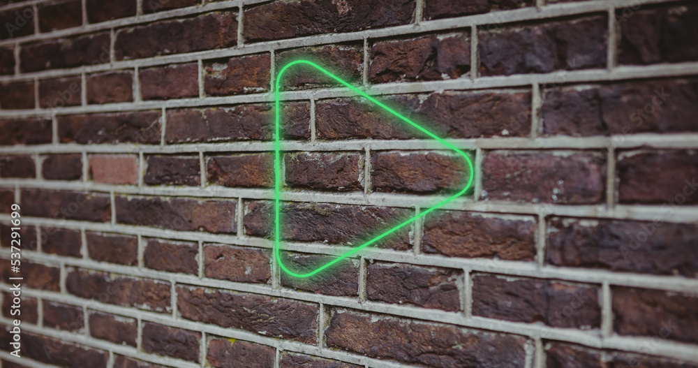 Composite of illuminated digital green play button icon against brick ...