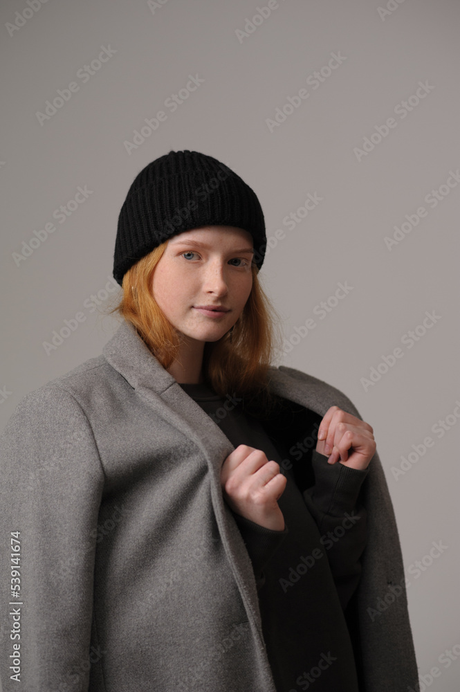 young girl model in black cap and grey jackett isolated on grey ...