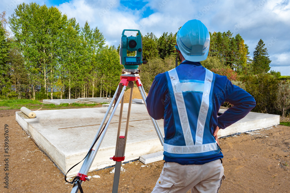 Geodetic works during construction. Man surveyor with his back to ...