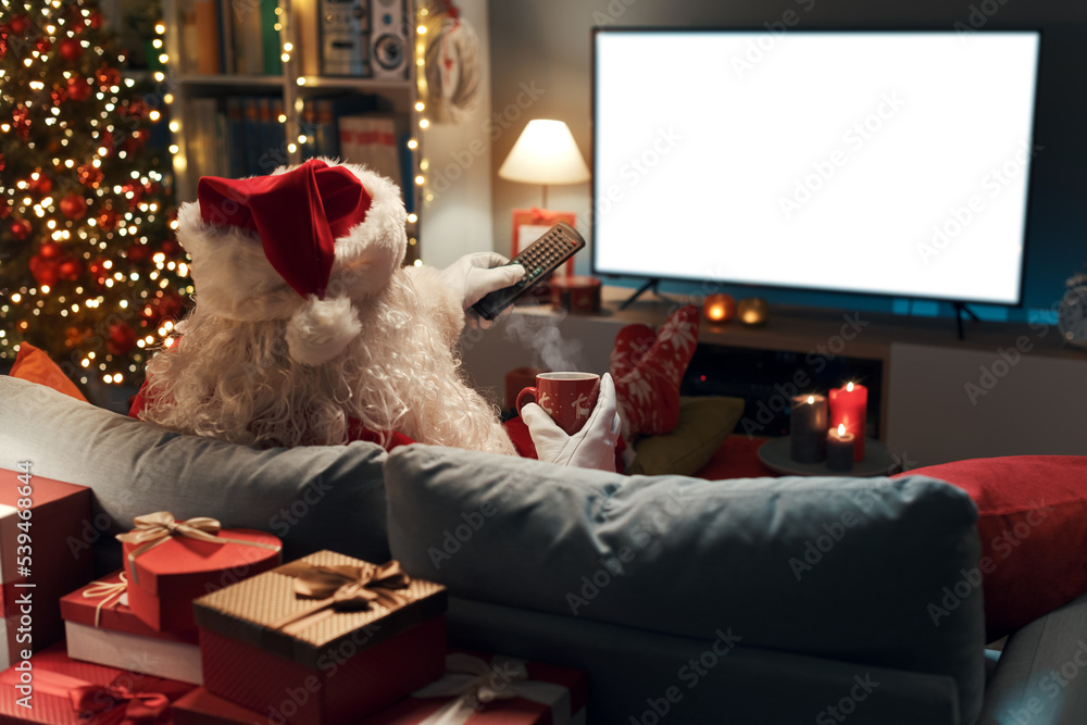 Foto de Stock Santa Claus watching television at home | Adobe Stock