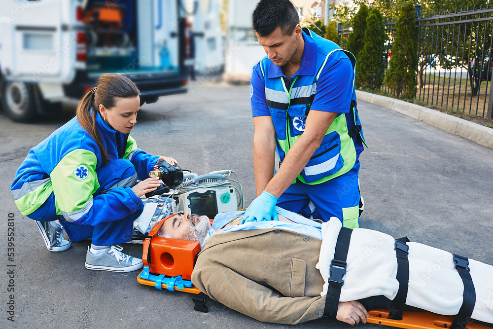 EMS paramedics performing closed-chest cardiac massage and artificial ...