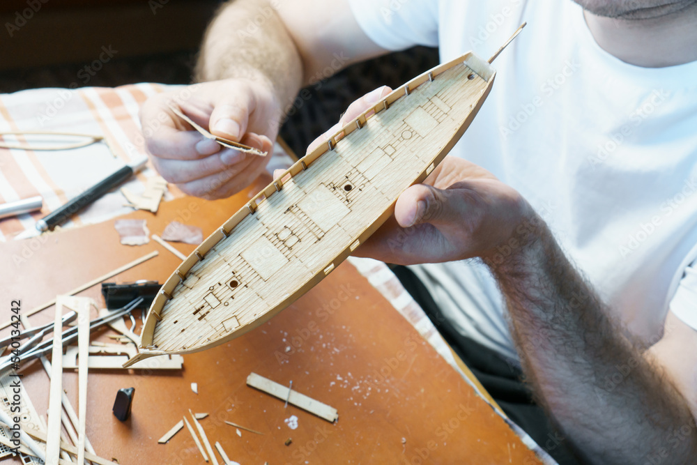 Hands of man adjusts plywood details for ship model, grinding on ...