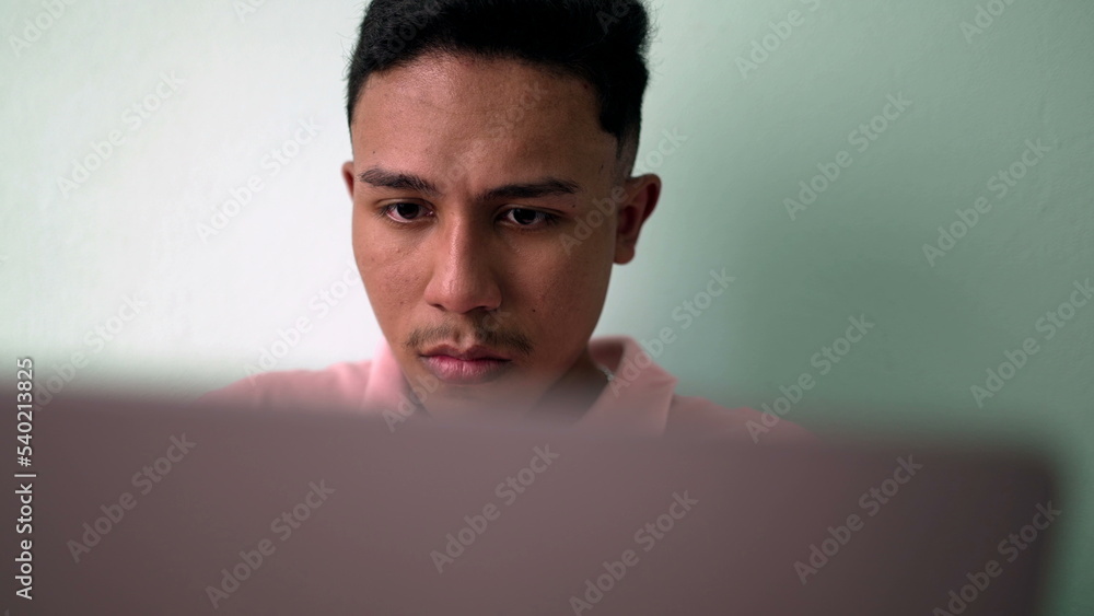 One hispanic young man browsing internet on laptop. Closeup face of ...