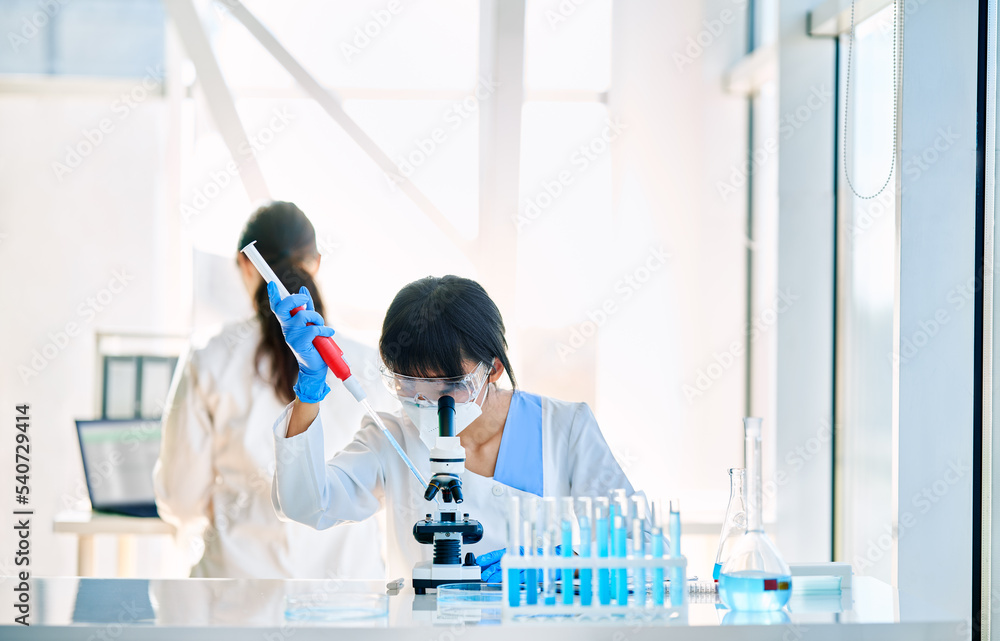 Beautiful female scientist preparing and analyzing microscope slides ...