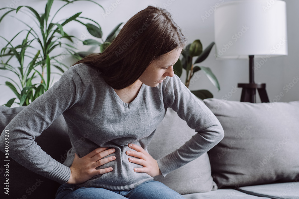 Sick young woman in pain holding belly stomach feeling hurt abdomen ...