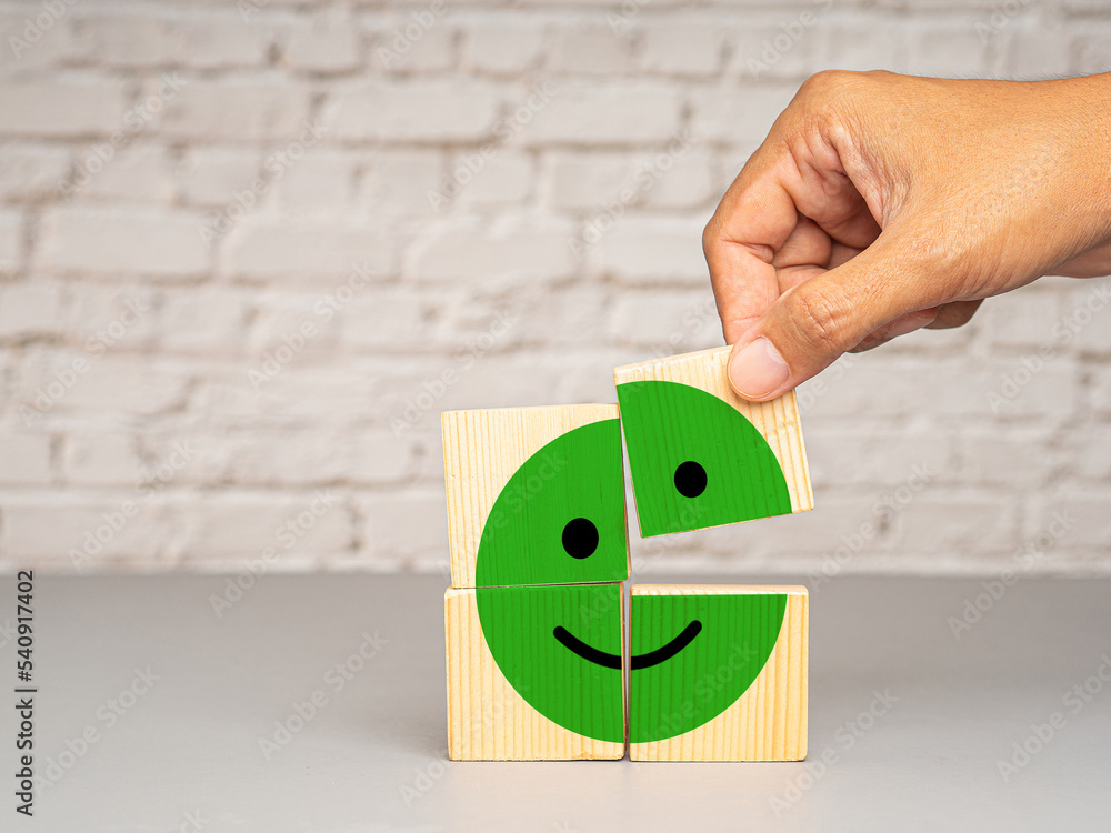 Positive feedback concept. Hand holding a green happy mood icon with a ...